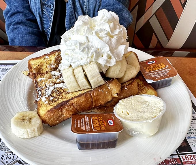 French toast that's dressed for a special occasion, complete with banana slices, whipped cream, and enough sweetness to make your coffee jealous.