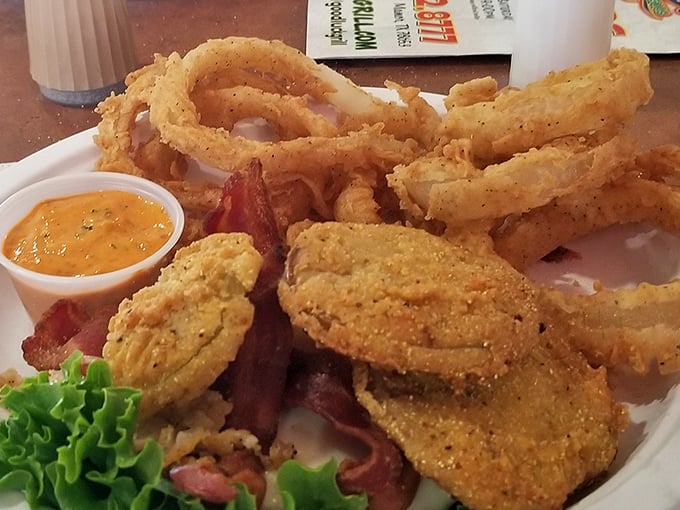 Fried green tomatoes and onion rings sharing a plate like old friends at a reunion, with a dipping sauce that deserves its own fan club.