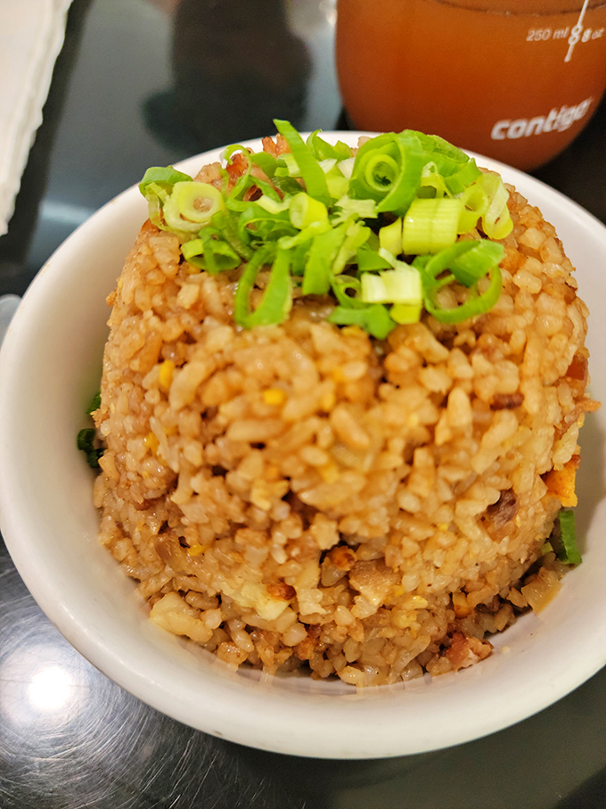 The fried rice arrives like a sculpted mountain of flavor, topped with fresh scallions that add a pop of color and zippy freshness to each hearty bite.