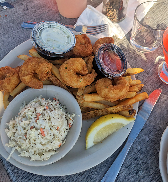 Golden fried shrimp nestled beside coleslaw and fries, with tartar sauce standing by for dipping duty.