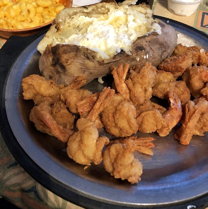 A plate of fried shrimp that would make coastal restaurants jealous, nestled beside a loaded baked potato that's practically a meal unto itself.