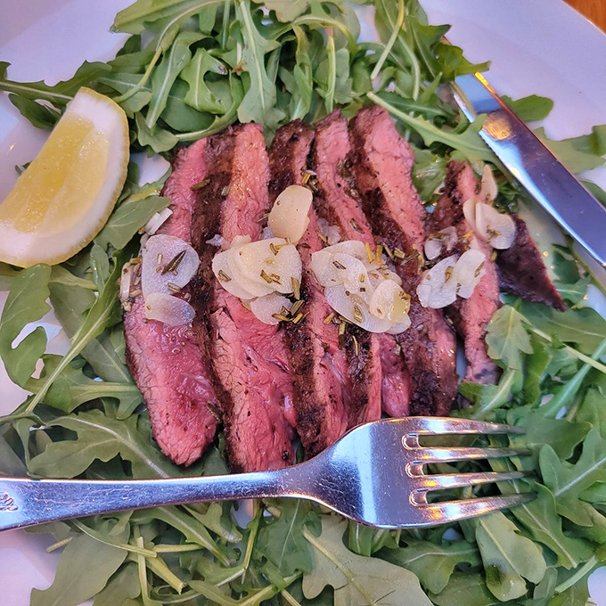 Perfectly grilled beef tagliata resting on peppery arugula with sweet onions&mdash;proof that Nostrana's talents extend well beyond their famous pizzas.