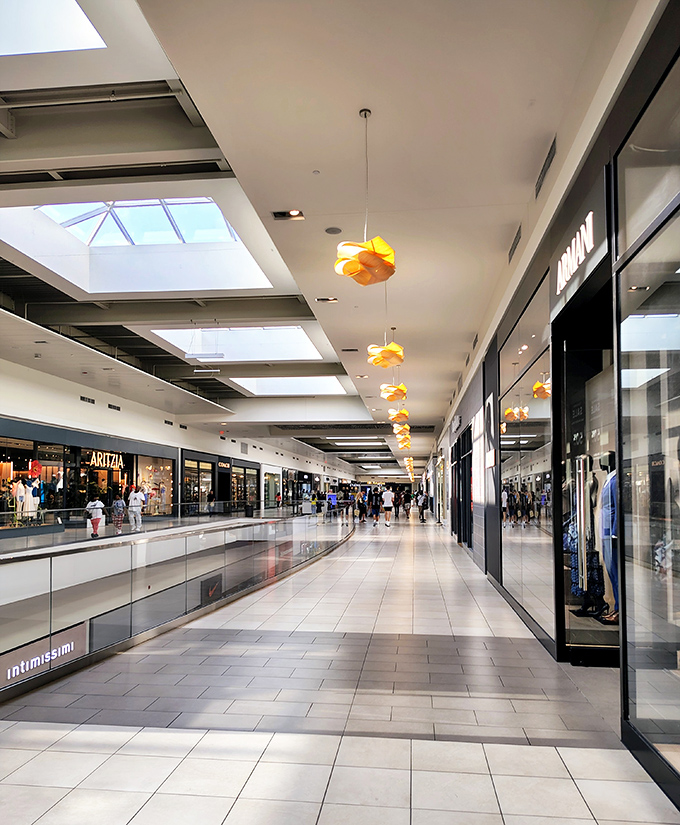 Sunlight streams through skylights onto pristine corridors that stretch like runways. Those orange pendant lights? They're guiding you to your next great find.