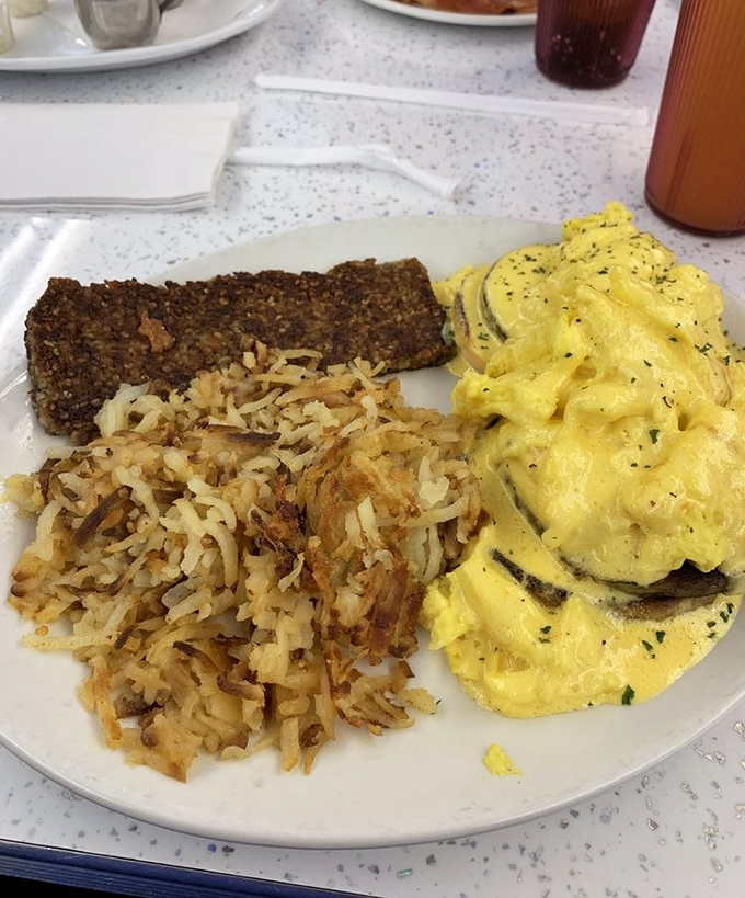 A breakfast trinity that would make any morning holy: perfectly scrambled eggs, crispy hash browns, and scrapple that your doctor wouldn't approve of.