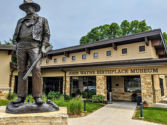 The Duke himself stands guard outside his birthplace museum, forever frozen in that iconic stance that launched a thousand Western showdowns.