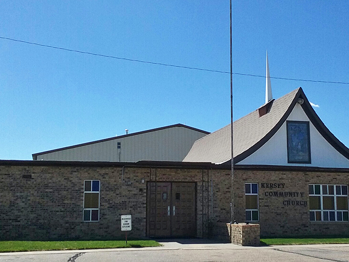 Kersey Community Church welcomes worshippers with its distinctive peaked roof, a spiritual landmark against the brilliant Colorado blue sky.