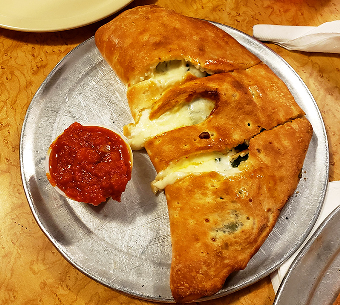 The calzone: pizza's more mysterious cousin. This golden-brown beauty oozes cheese like it's making a jailbreak for your taste buds.