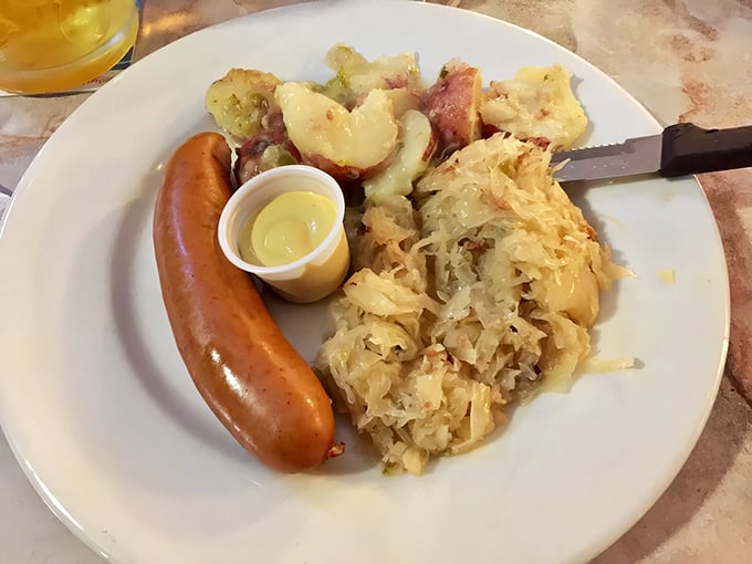 A proper German sausage lounging beside tangy sauerkraut and potato salad – comfort food that transcends language barriers.