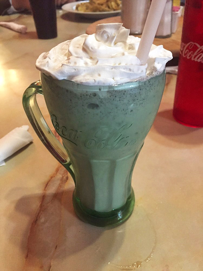 This isn't just a milkshake; it's a frothy green masterpiece topped with whipped cream mountains in a vintage glass.