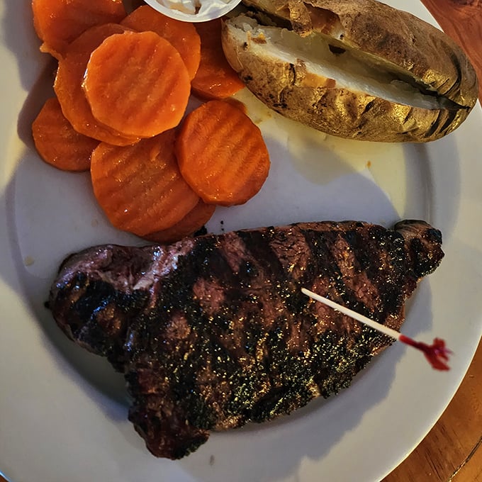 A steak with perfect grill marks served alongside a baked potato that's practically begging to be smothered in toppings.