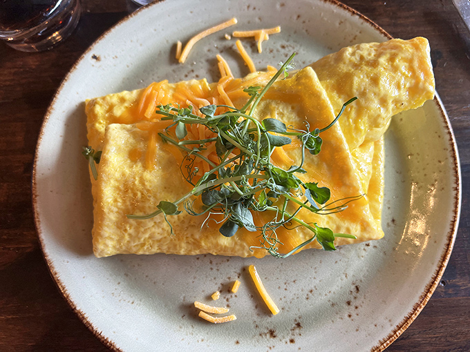 This omelet doesn't just sit on the plate&mdash;it lounges there confidently, draped in melted cheese with microgreens adding a pop of color and freshness.