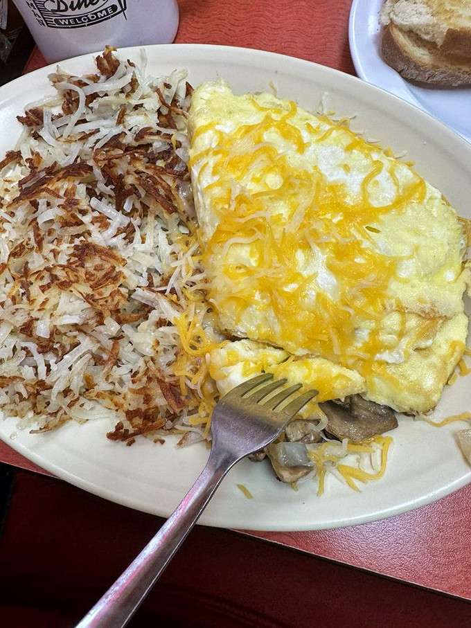 A cheese omelet that's achieved perfect fluffiness alongside hash browns with the ideal crisp-to-tender ratio—breakfast engineering at its finest.