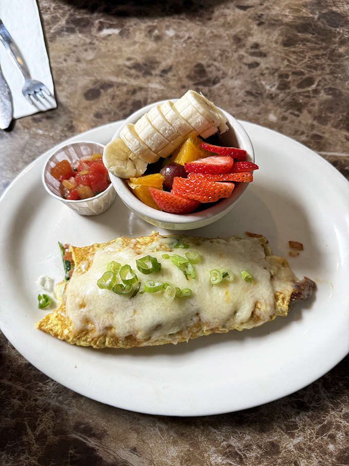 This omelet, draped in melted cheese and topped with green onions, comes with a side of fruit that makes you feel virtuous.
