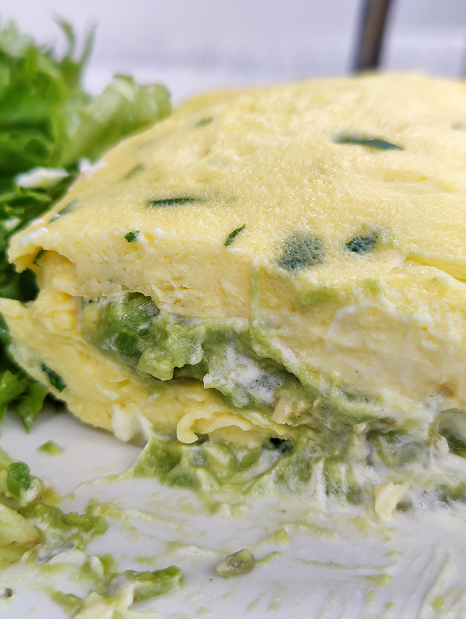 Eggs transformed into cloud-like perfection, with vibrant green vegetables folded in like secrets. This omelet whispers "I'm healthy" while shouting "I'm delicious!"