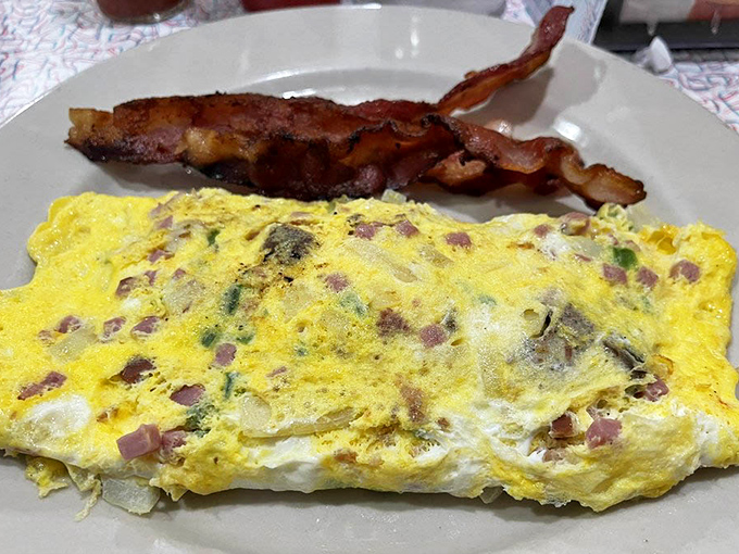 This omelet doesn't just contain ingredients; it showcases them alongside bacon that's achieved that perfect crispy-yet-chewy texture breakfast dreams are made of.