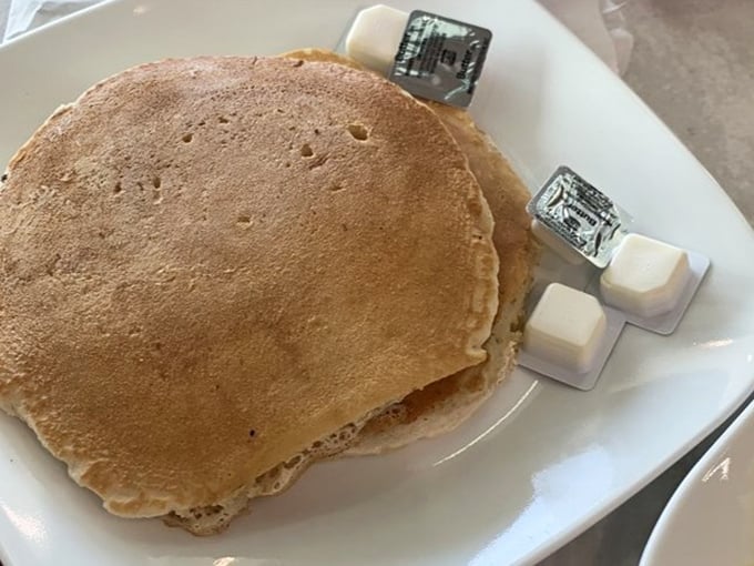 Fluffy pancakes with butter pats still wrapped like tiny presents &ndash; simple pleasures that never go out of style, thank goodness.