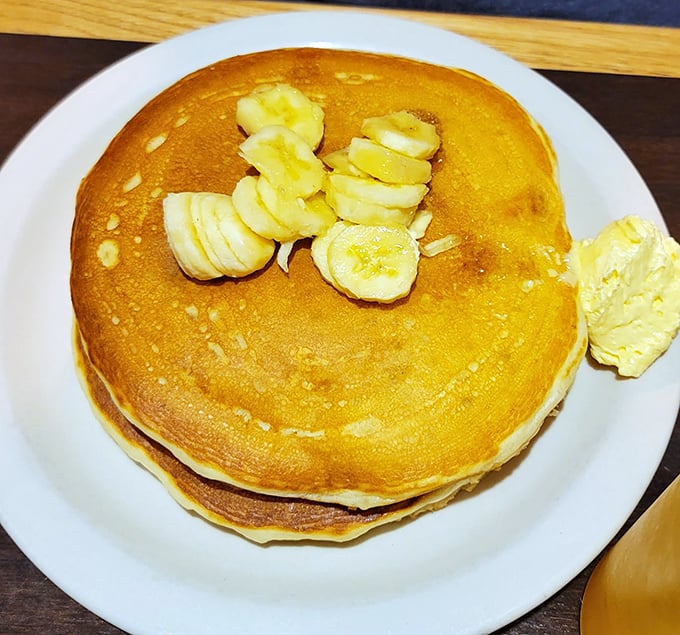 Behold the pancake in its natural habitat—golden, fluffy, and adorned with banana slices like a crown. Breakfast royalty, no question.
