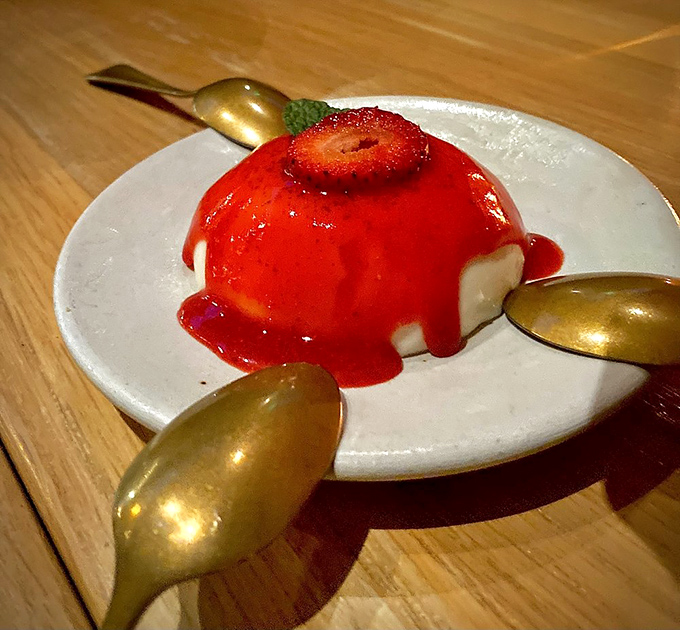 Panna cotta that quivers with anticipation, draped in strawberry sauce like a dessert that dressed up for a special occasion just to meet you.