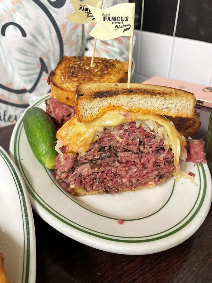 This isn't just a sandwich; it's a skyscraper of pastrami requiring architectural planning before each bite. The pickle stands guard like a delicious sentry.