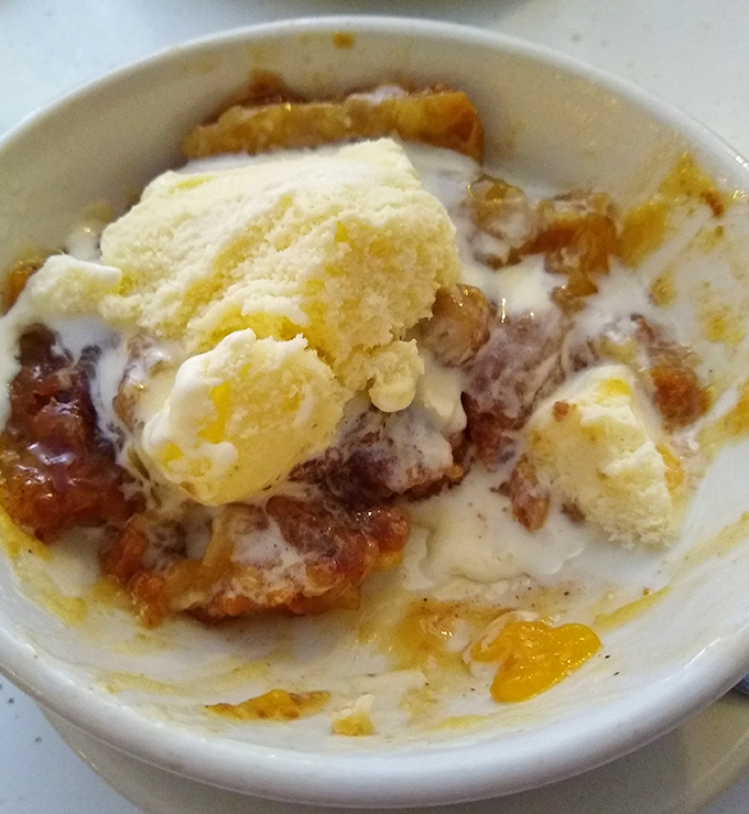 Peach cobbler with ice cream: where fruit technically counts as healthy even when swimming in cinnamon-sugar bliss.