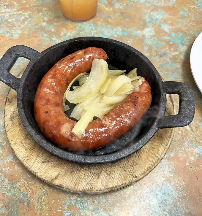 Portuguese sausage served in a cast iron skillet with sweet onions &ndash; proof that sometimes the simplest dishes deliver the most profound satisfaction.