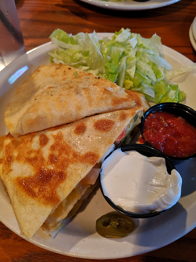 This quesadilla isn't just folded—it's transformed into a crispy, cheese-oozing envelope of joy, with those dipping sauces standing by like faithful companions.