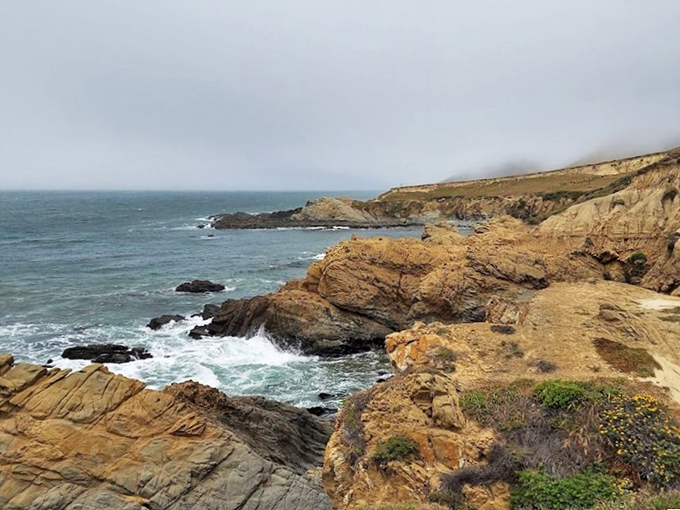 Moody skies transform the rugged coastline into a dramatic stage where waves crash against ancient rocks in nature's perpetual performance art.