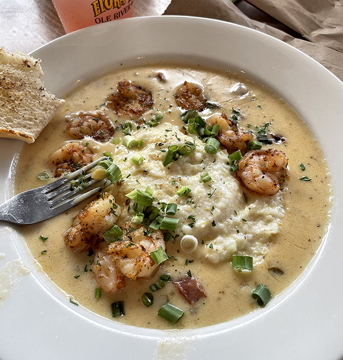 A bowl of coastal comfort&mdash;tender shrimp swimming in creamy grits with green onions standing at attention, ready to report for delicious duty.