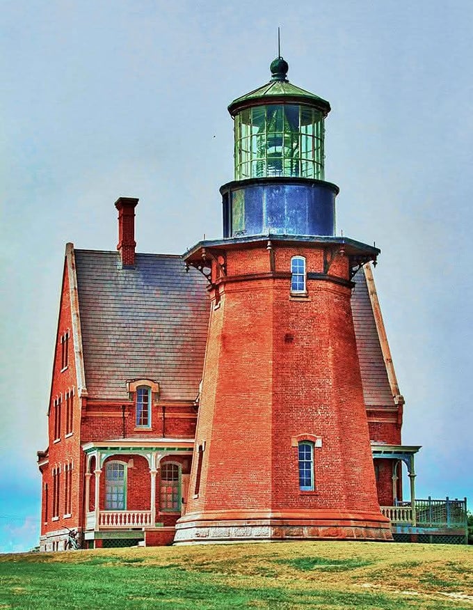 The brick-red Southeast Lighthouse stands like a Victorian sentinel, its copper-green top gleaming against the Rhode Island sky.