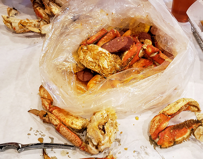 The plastic bag reveals its treasures—crab legs and potatoes swimming in spiced glory. Seafood Christmas comes in transparent packaging.