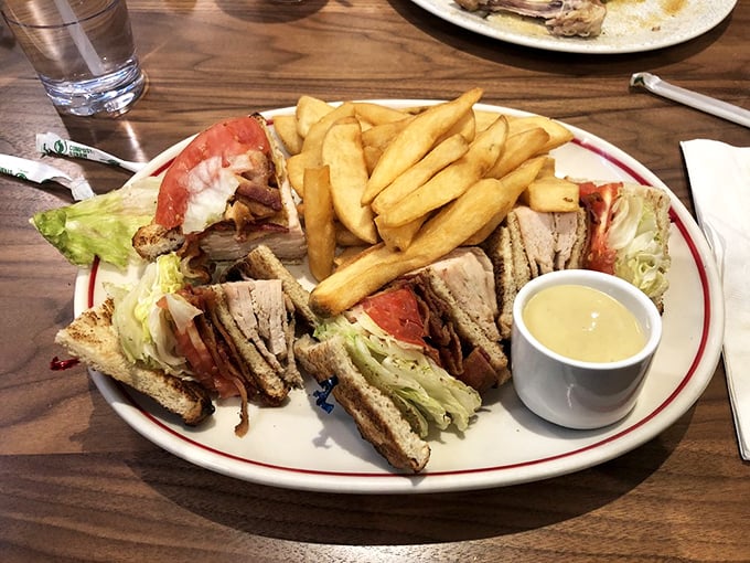 The club sandwich—architecture you can eat. Three perfectly stacked stories of turkey, bacon, and toast that require both hands and absolutely zero shame.