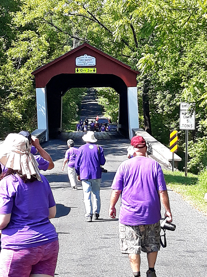 Visitors in matching purple shirts approach the bridge, perhaps a tour group discovering one of Bucks County's most photogenic historical treasures.