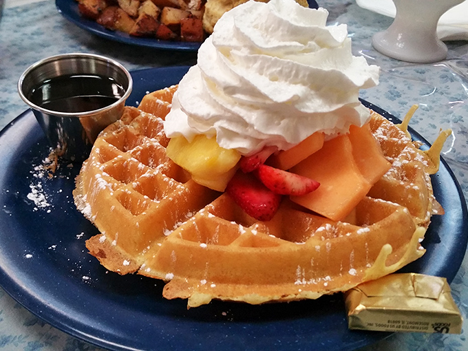 A golden waffle crowned with fresh fruit and whipped cream that stands taller than your morning hair. Breakfast or dessert? The line deliciously blurs.