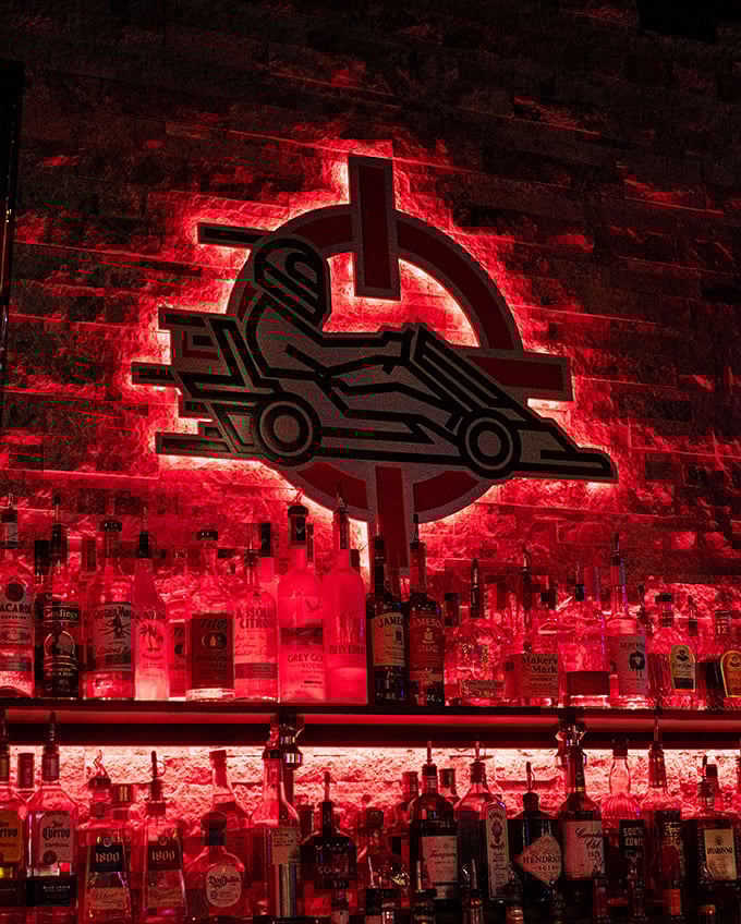 The bar glows with the same red intensity as your racing heart, offering liquid courage before your next lap.