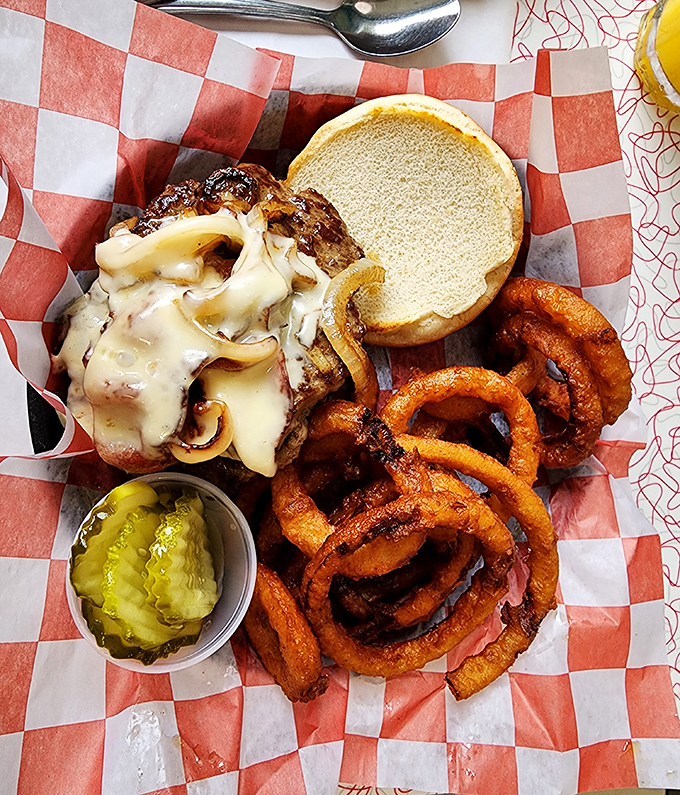 The mushroom Swiss burger arrives like a beautiful science experiment&mdash;melted cheese cascading over saut&eacute;ed mushrooms with onion rings standing guard.