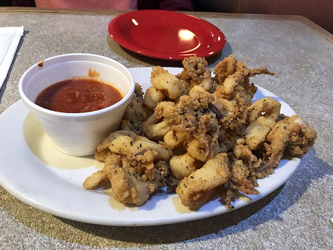 Crispy, perfectly fried calamari rings and tentacles, served with that bright red dipping sauce—a universally joyful, crunchy bite of the sea.
