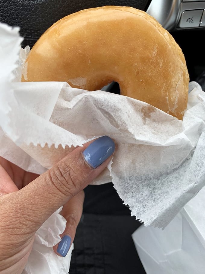 The humble glazed donut, elevated to art form. This golden beauty, wrapped in tissue, represents everything right with the world at 7am.