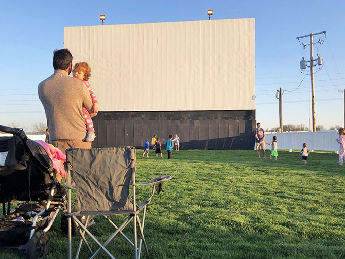Parents watch as children burn off pre-movie energy, turning the grassy area into an impromptu playground. Who needs assigned seating?
