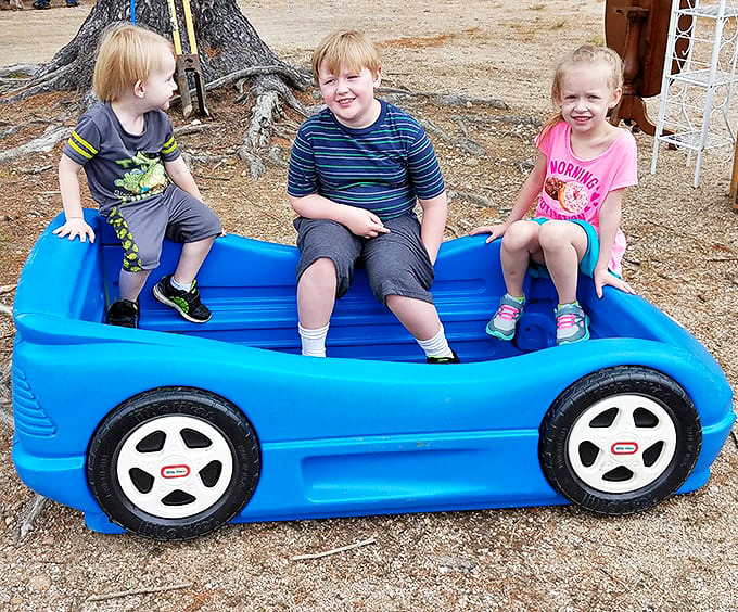 Three young treasure hunters test-driving their find – proving that one person's outgrown toy becomes another child's Sunday afternoon adventure.