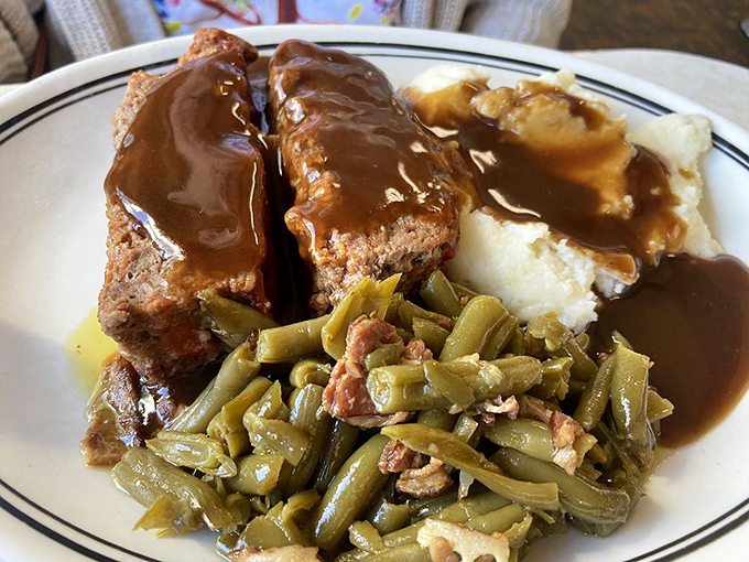 Behold the star attraction—meatloaf that would make your grandmother both jealous and proud, bathed in gravy that deserves its own fan club.