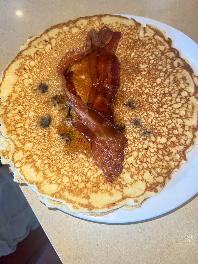Whoa, this pancake is as big as a vinyl record! That single, perfectly crisp strip of bacon is the crown jewel on this sweet stack.