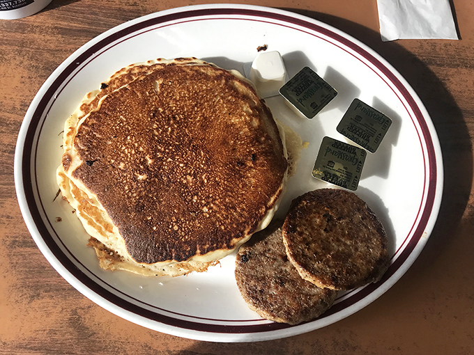 Golden pancakes with a side of sausage patties&mdash;breakfast's perfect power couple. The butter packets stand by, ready for their supporting role.