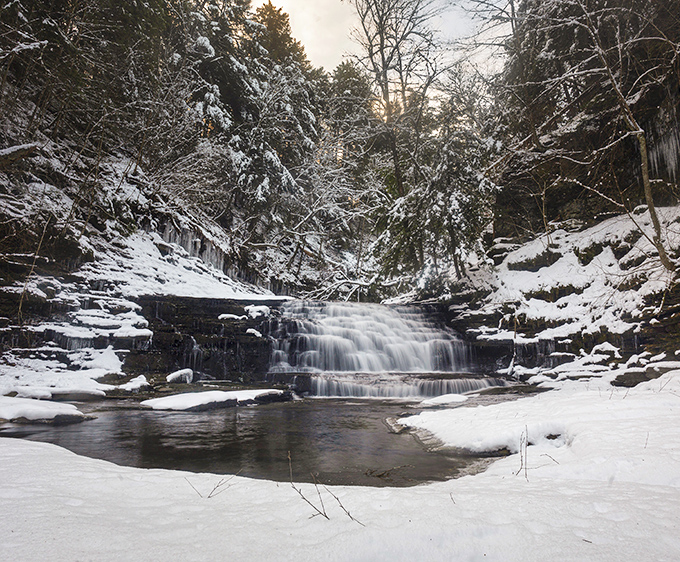Winter transforms the falls into a breathtaking ice sculpture garden. The contrast of flowing water against snow-covered rocks creates nature's perfect postcard.