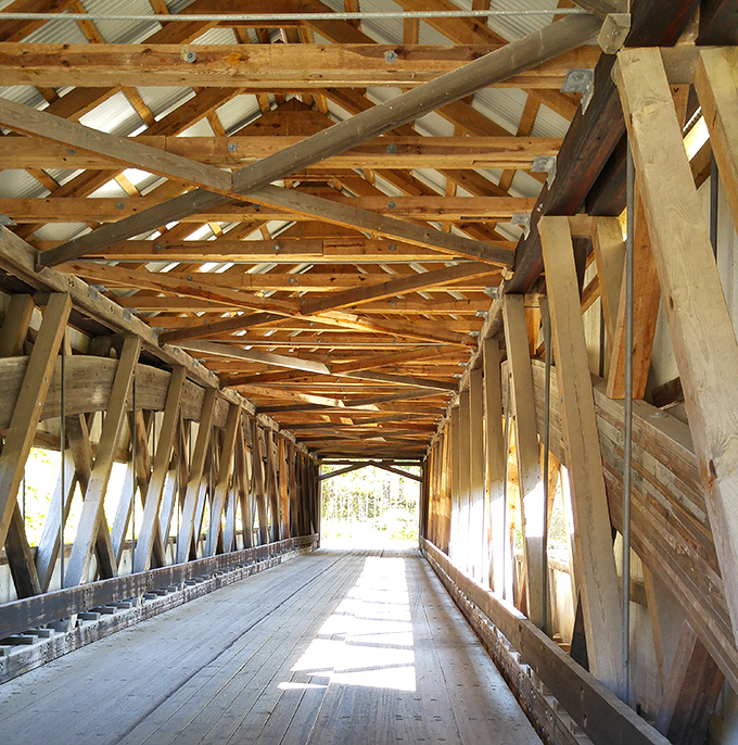 Sunlight plays hide-and-seek through the lattice truss work, creating an ever-changing light show on the worn wooden planks below. 