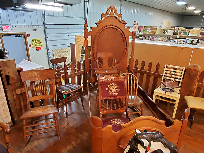 A parliament of wooden chairs holds court, each with its own personality. That ornate headboard has definitely seen some history.