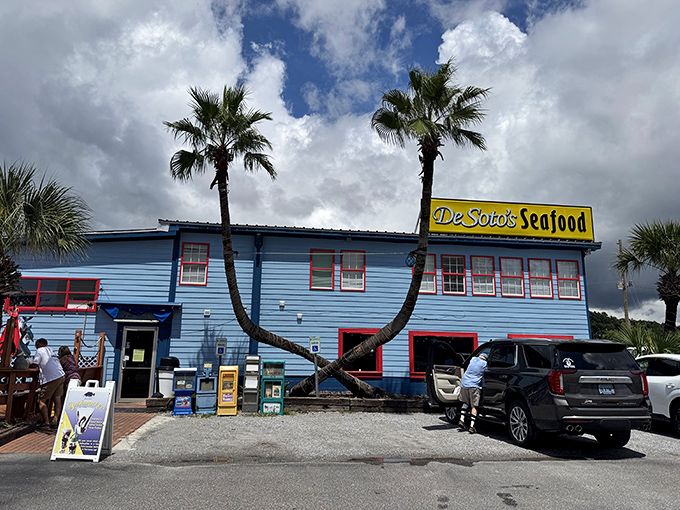 DeSoto's Seafood Kitchen bright blue building with those iconic crossed palm trees is Gulf Shores' answer to seafood paradise. Beach vibes with serious flavor!