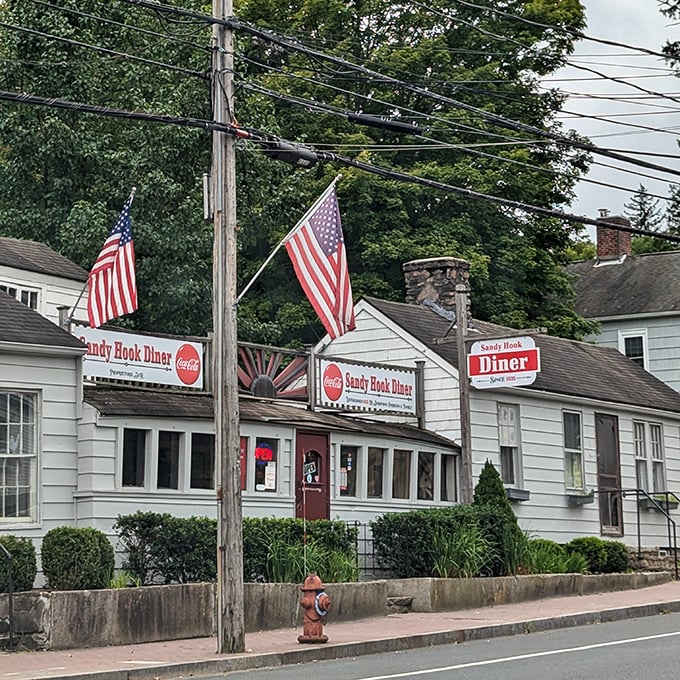 Sandy Hook Diner's white cottage charm and American flags create the perfect small-town welcome. This unassuming spot has been serving breakfast dreams since FDR was president.
