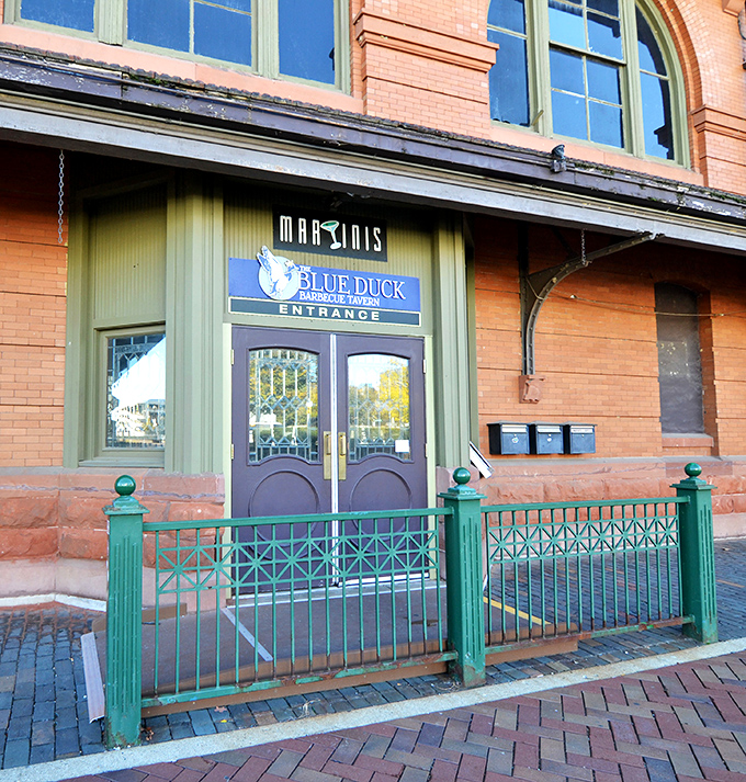 Historic architecture frames the Blue Duck entrance where barbecue tradition meets downtown charm along the scenic riverfront.