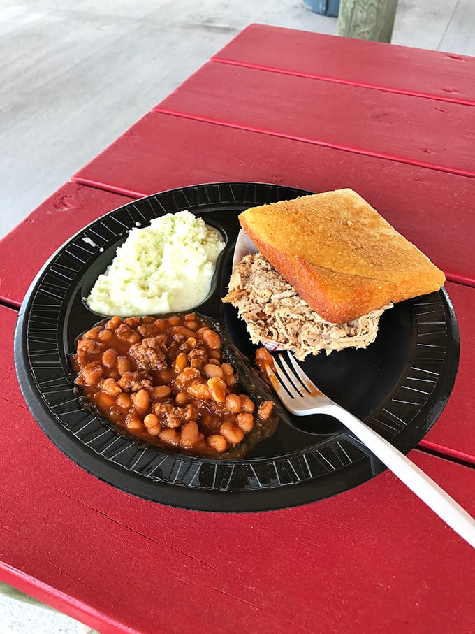 The perfect BBQ tray: chopped whole hog pork sandwich with golden cornbread, creamy slaw, and savory baked beans.