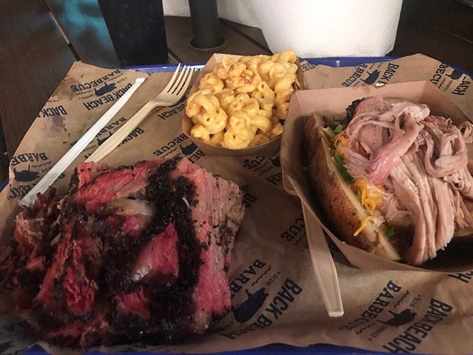 The barbecue plate that makes photographers forget to eat. Brisket with that telltale smoke ring, mac and cheese, and a sandwich that's basically meat architecture.
